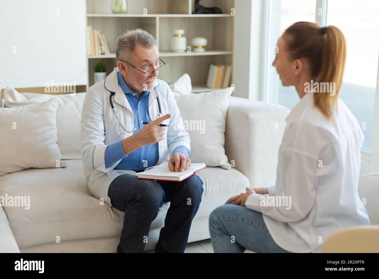 Senior man doctor examining yound woman in doctor office or at home ...