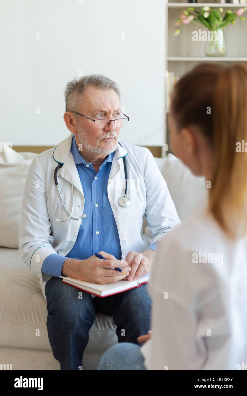 Senior man doctor examining yound woman in doctor office or at home ...