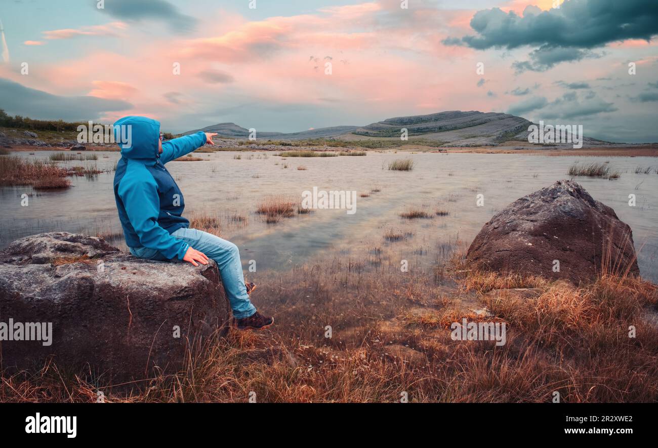 Beautiful sunrise landscape scenery with man sitting on the rock by the ...