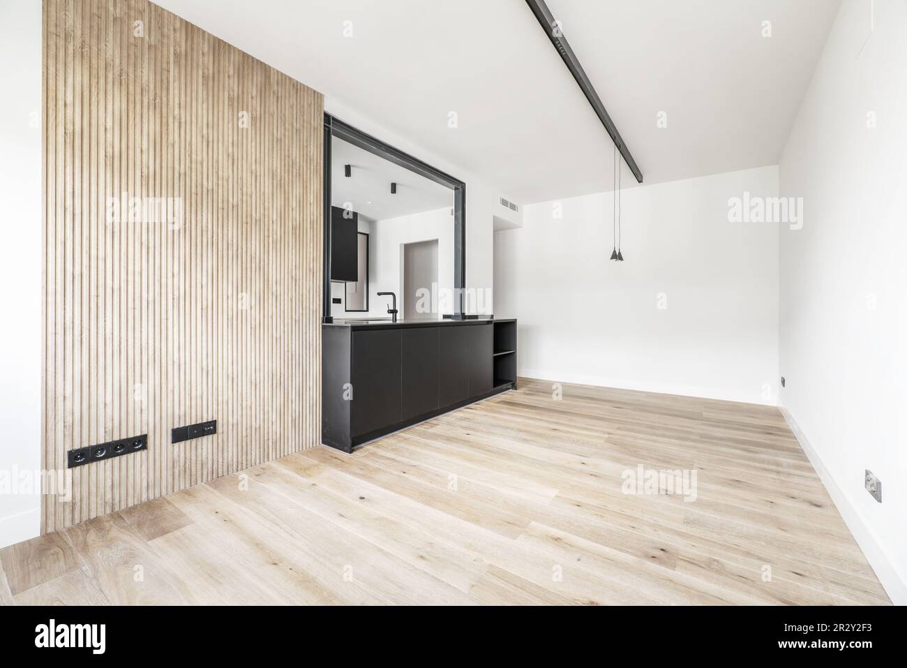 Living room with white walls with a wooden mural and a kitchen ...