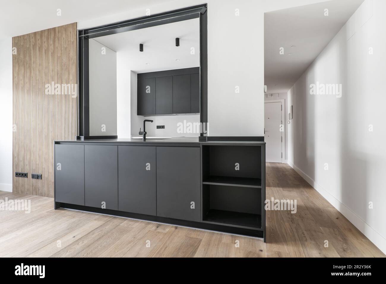 White walled living room with a kitchen equipped with serving hatch and ...