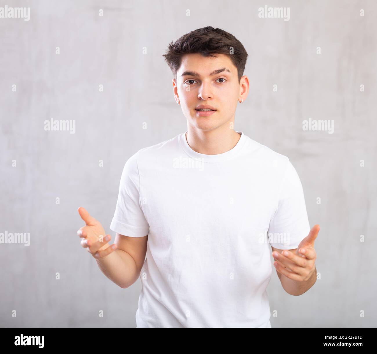 Disputing young man standing against background of grey unicolored wall ...