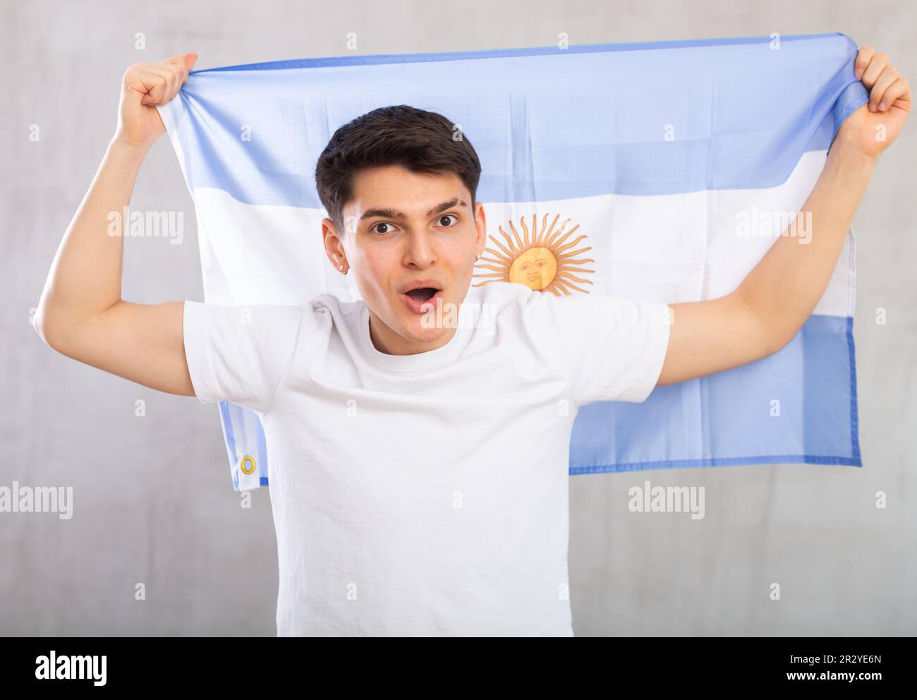 Agitated sports male fan holds canvas of national flag of Argentina in ...