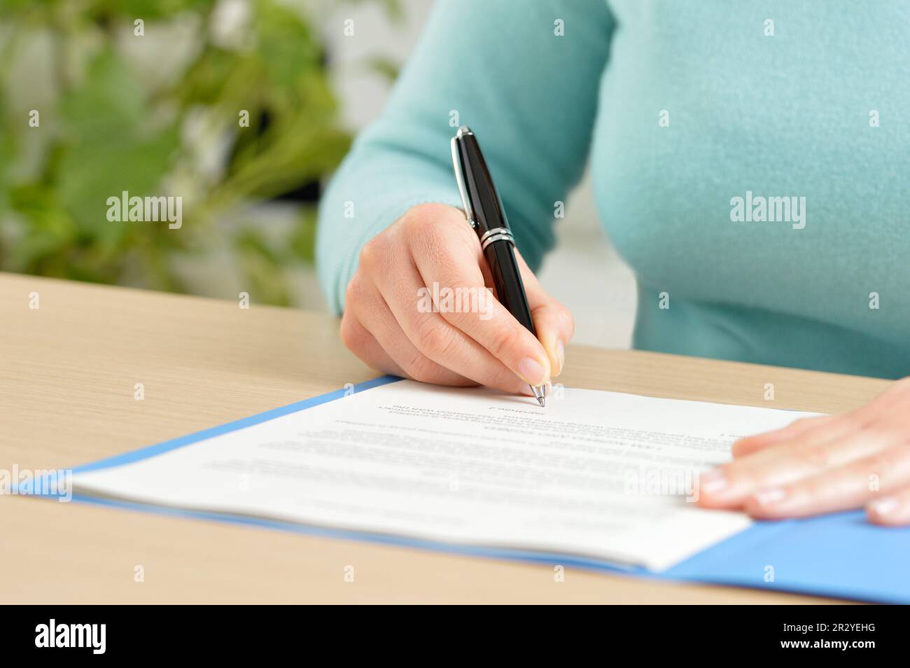 Close up front view portrait of a hand signing a contract on a desktop ...