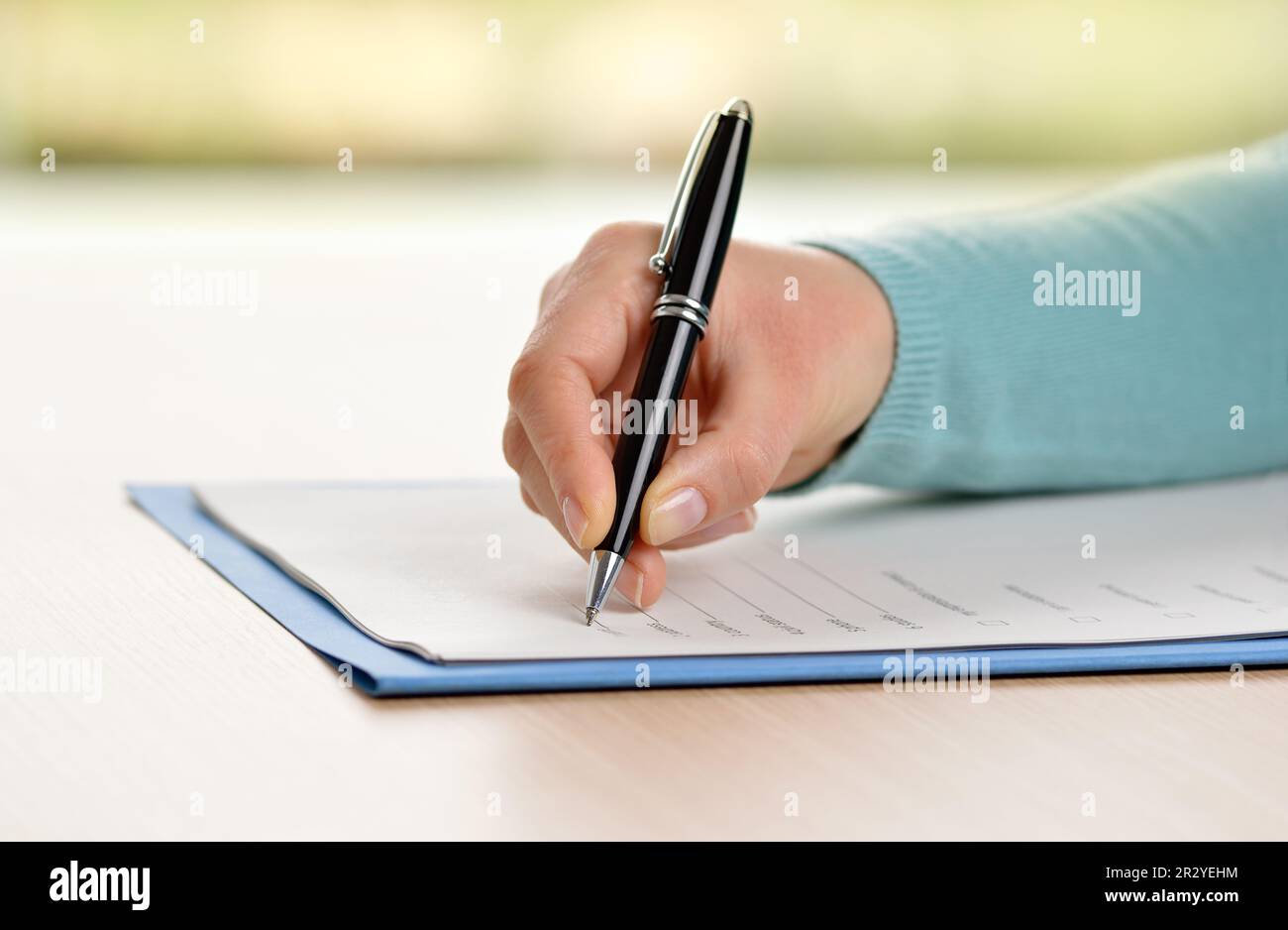 Close up of woman hand filling form on a table Stock Photo - Alamy
