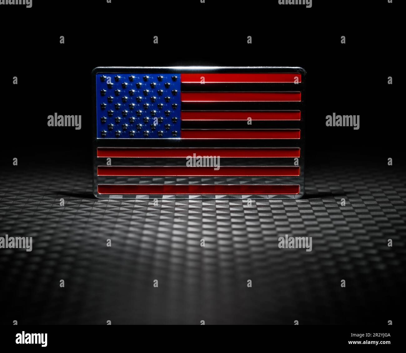 Spotlight on shiny US American flag emblem on dark carbon fiber ...