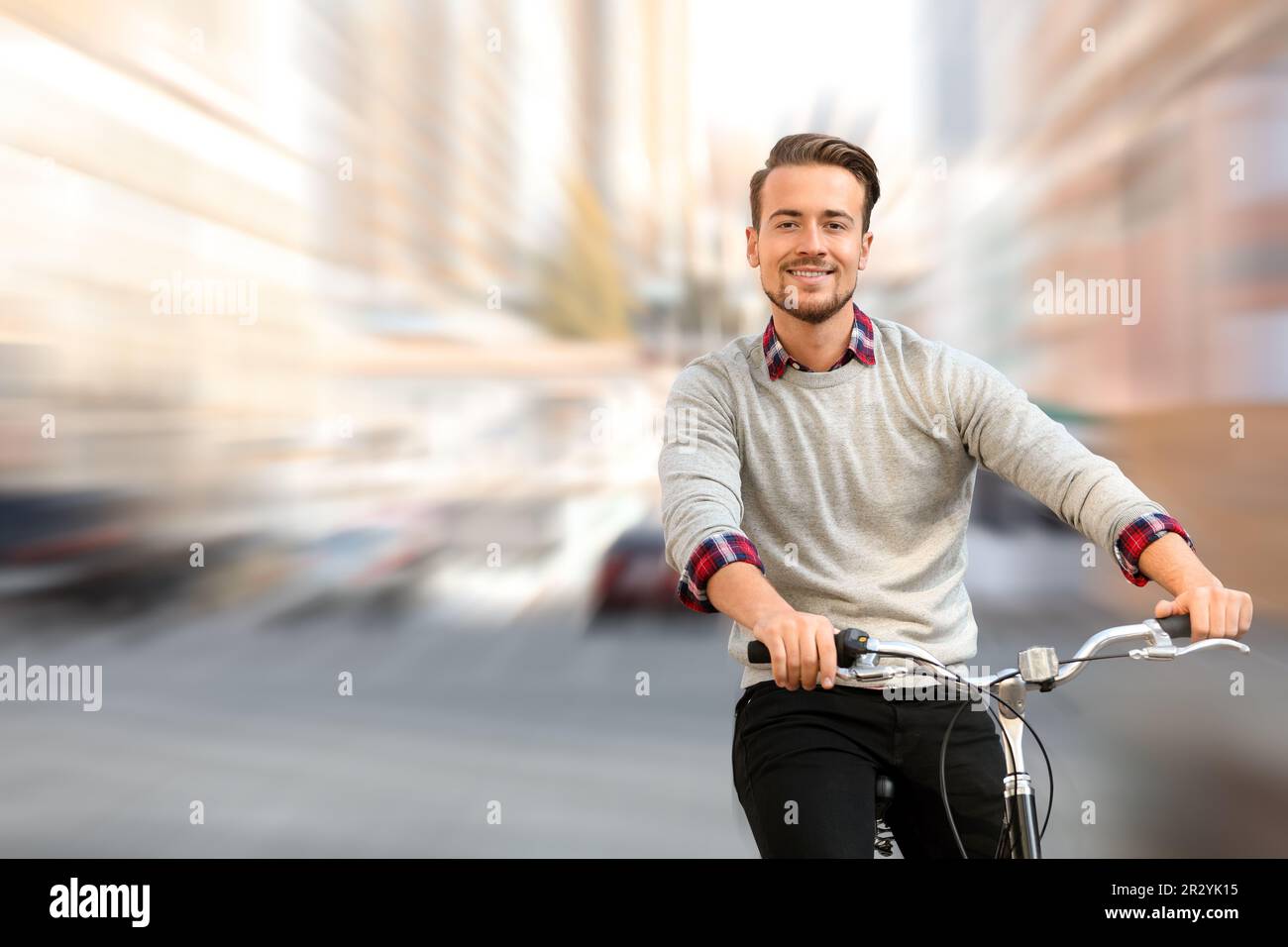 Handsome happy man riding bicycle on city street, motion blur effect ...