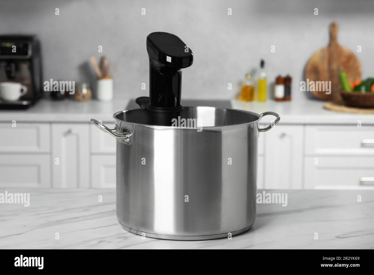 Pot with sous vide cooker on table in kitchen. Thermal immersion ...