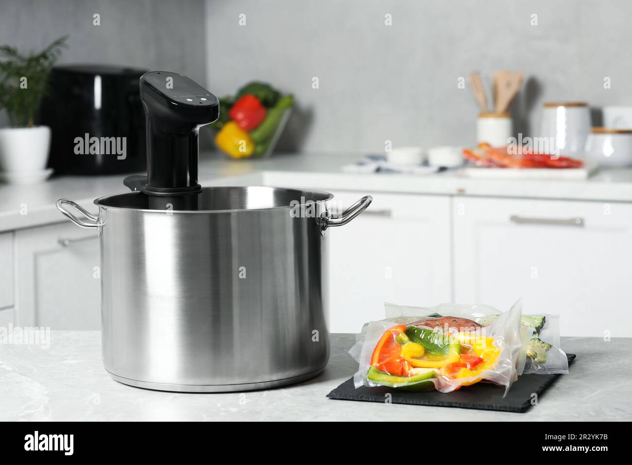 Pot with sous vide cooker and vacuum packed food products on table in ...