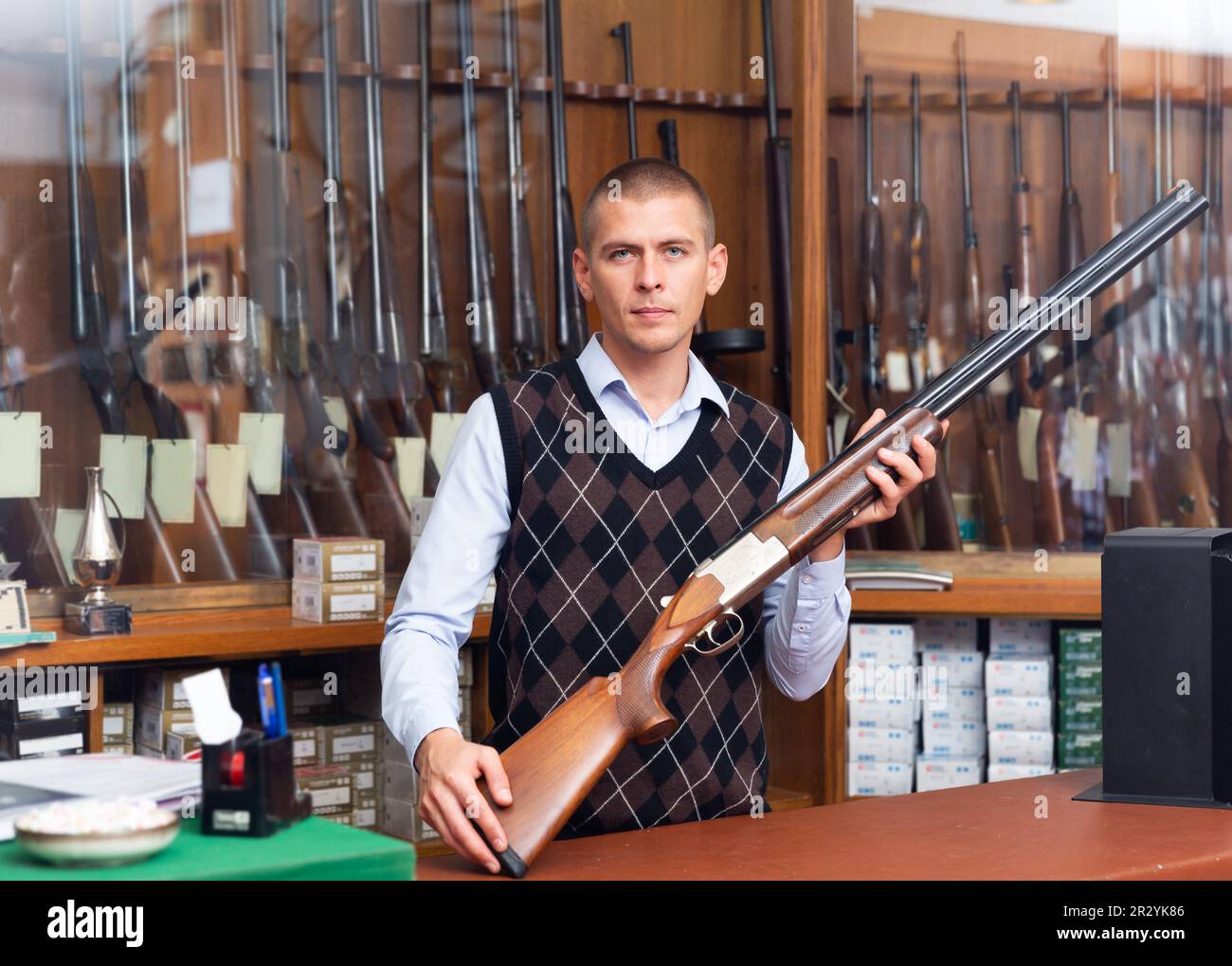 Gun shop salesman showing double barreled hunting rifle Stock Photo - Alamy