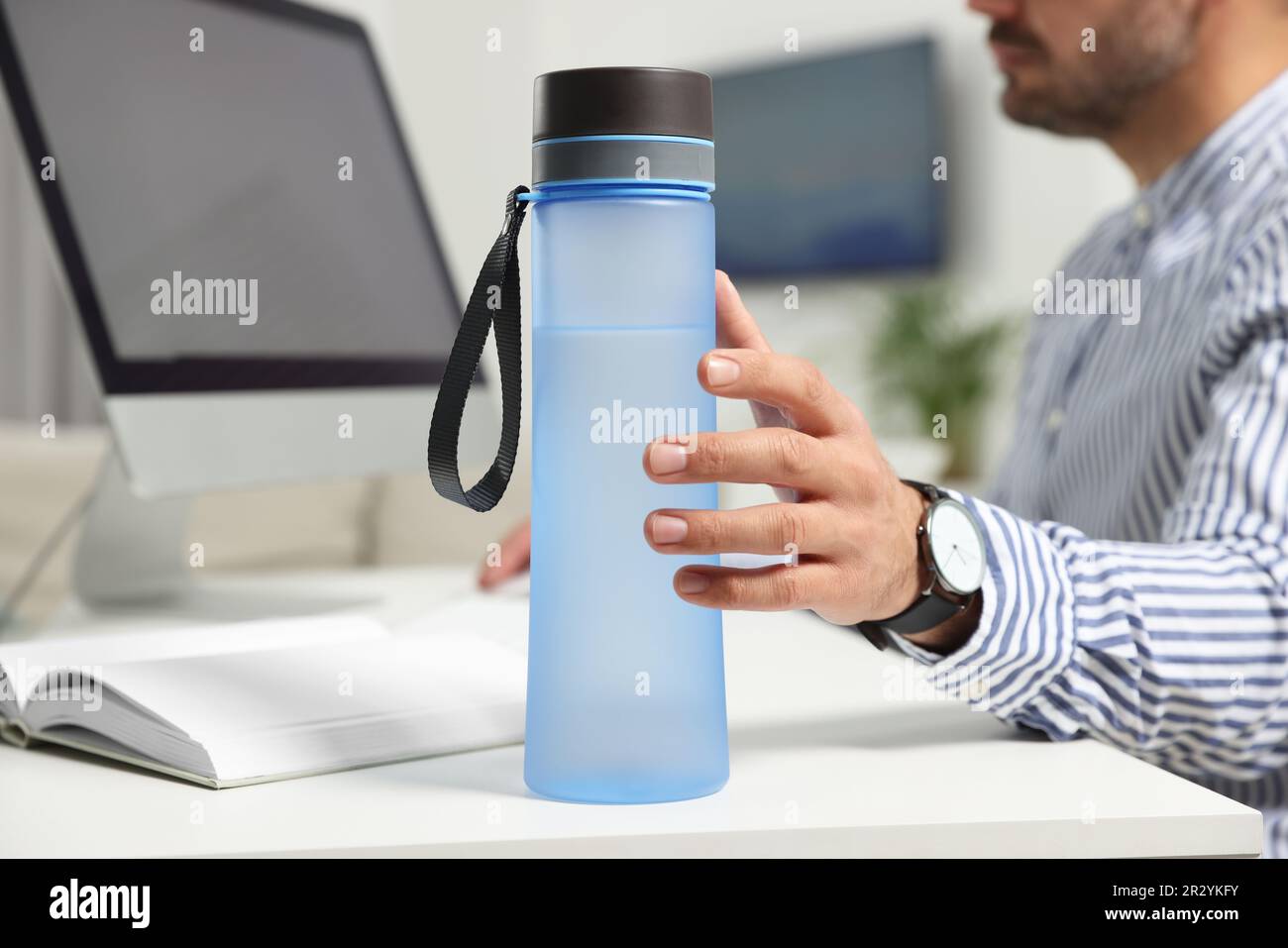 Man taking transparent plastic bottle of water while working on ...