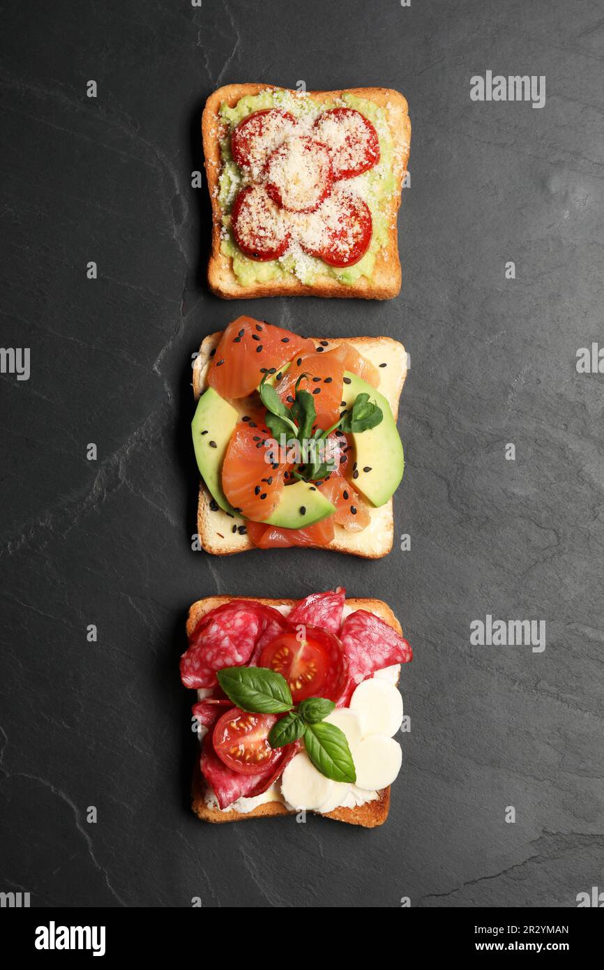 Tasty toasts with different toppings on black table, flat lay Stock ...