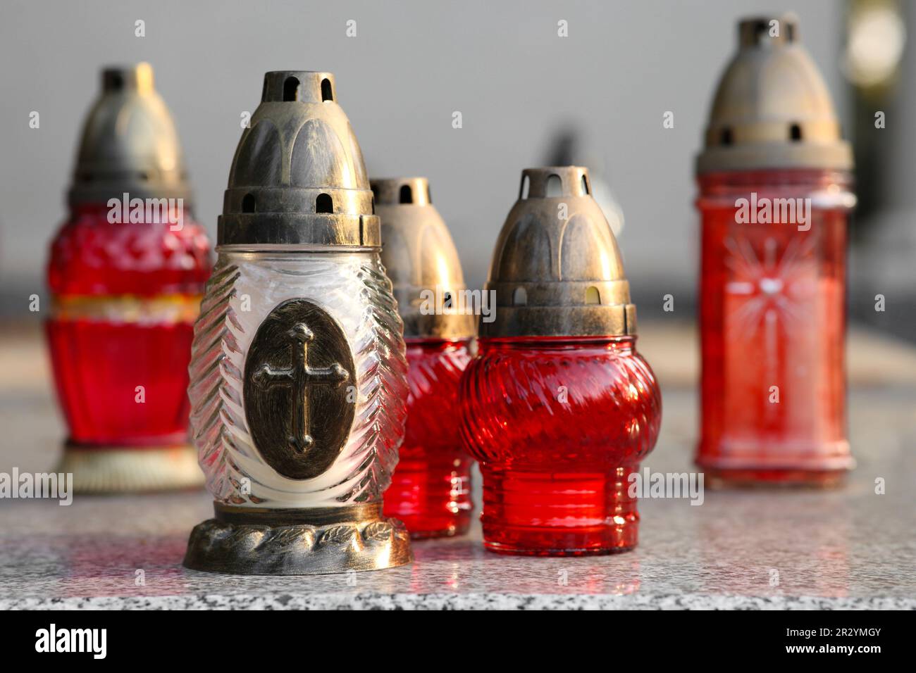 Different grave lanterns on granite tombstone outdoors. Funeral ceremony Stock Photo - Alamy
