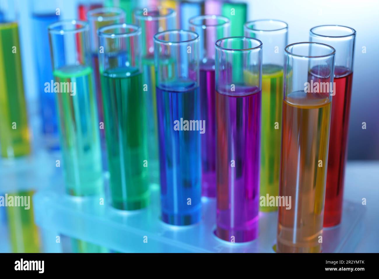 Many test tubes with colorful liquids on blurred background, closeup ...