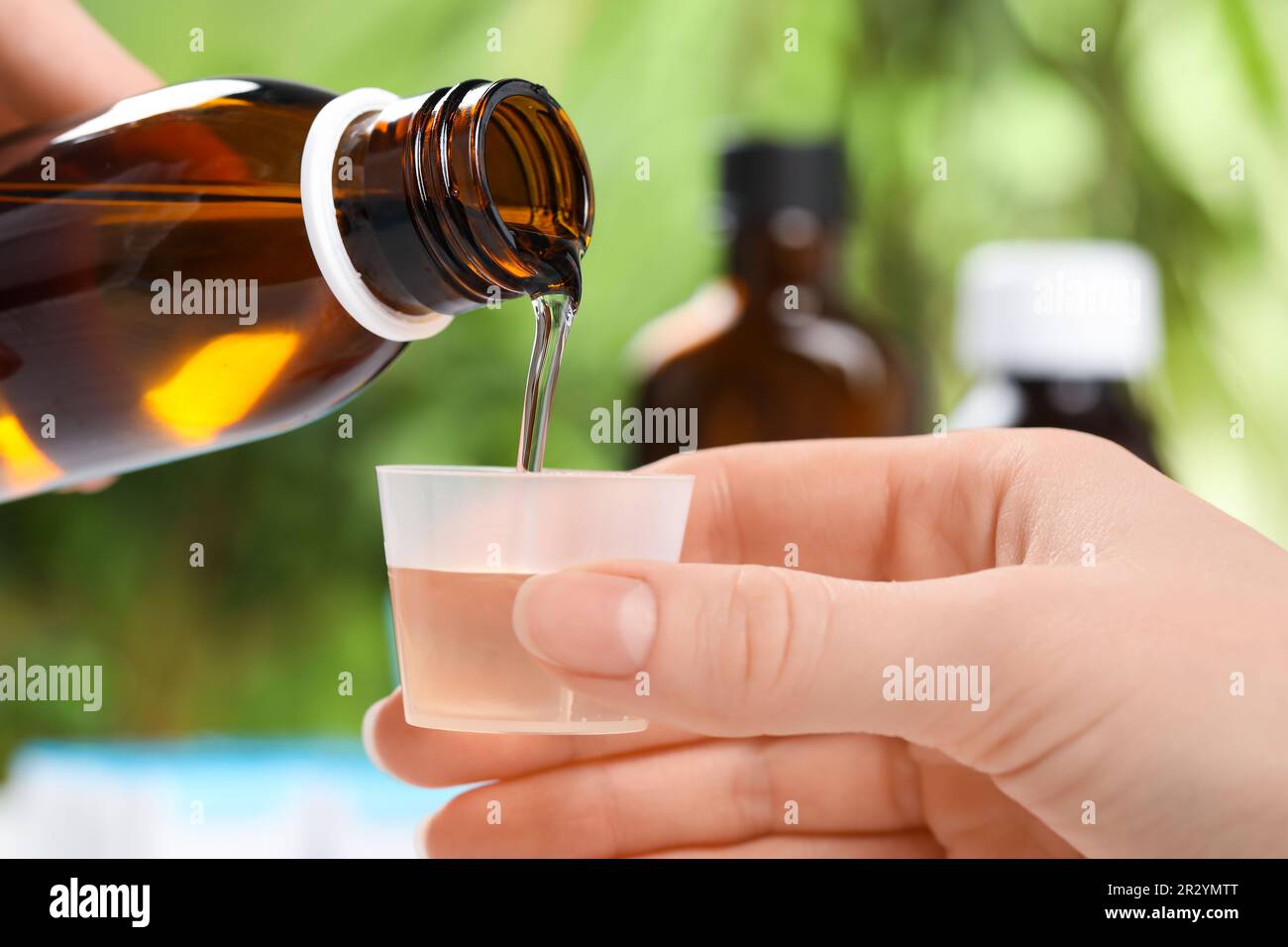 Woman pouring syrup from bottle into measuring cup on blurred ...