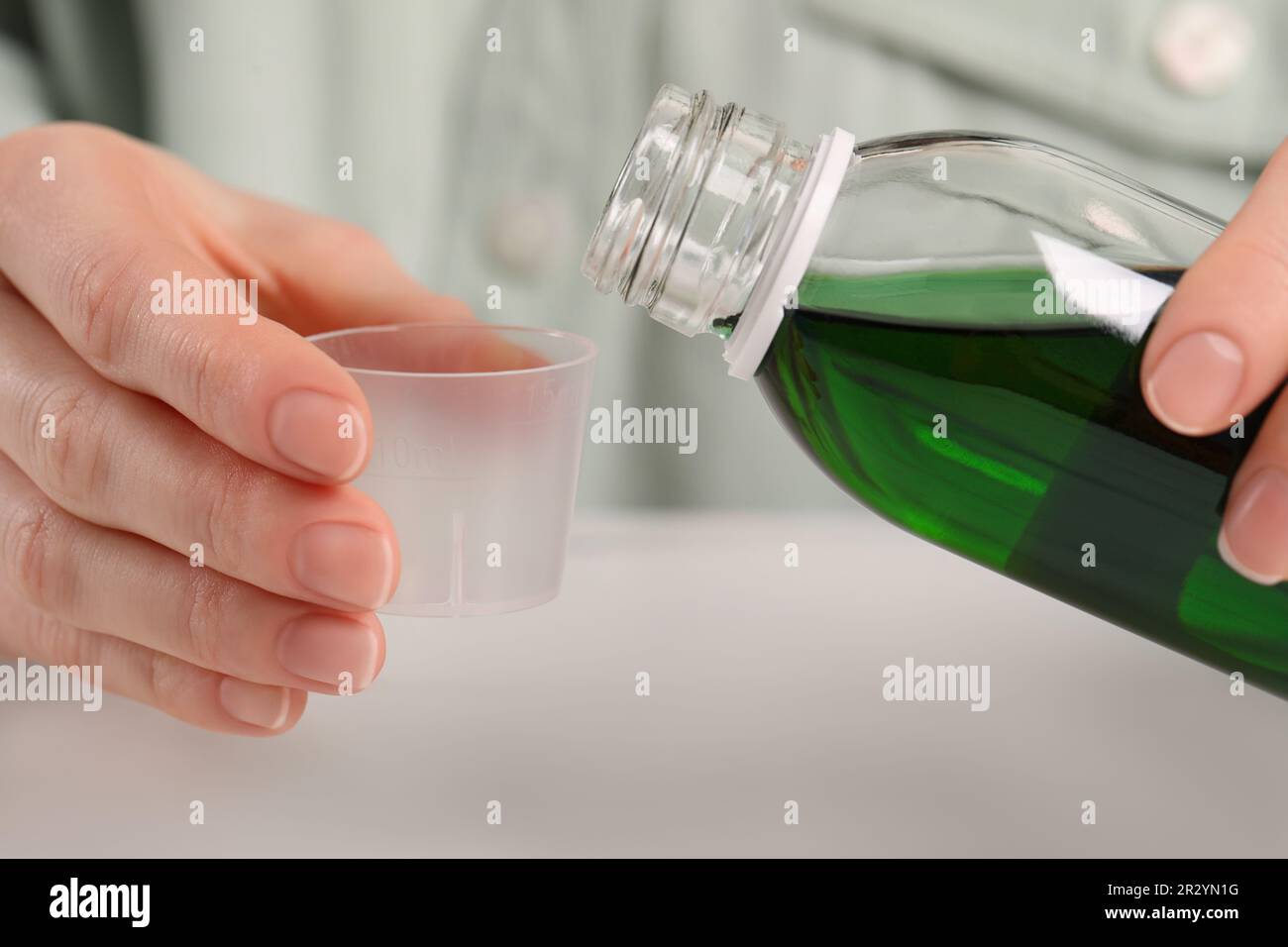 Woman pouring syrup from bottle into measuring cup at table, closeup ...