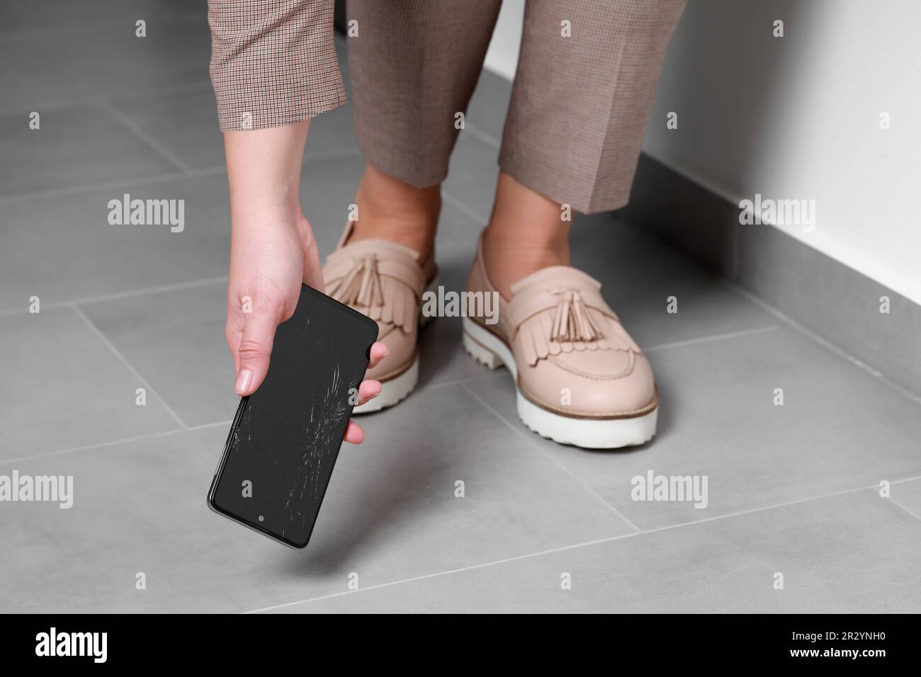 Woman taking dropped smartphone from floor, closeup. Device repairing ...