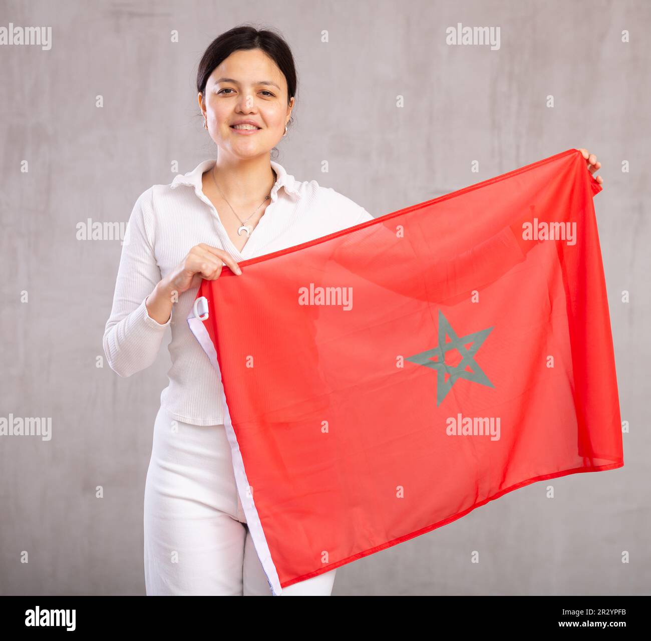 Positive middle aged woman holding an unfurled flag of Morocco in her ...