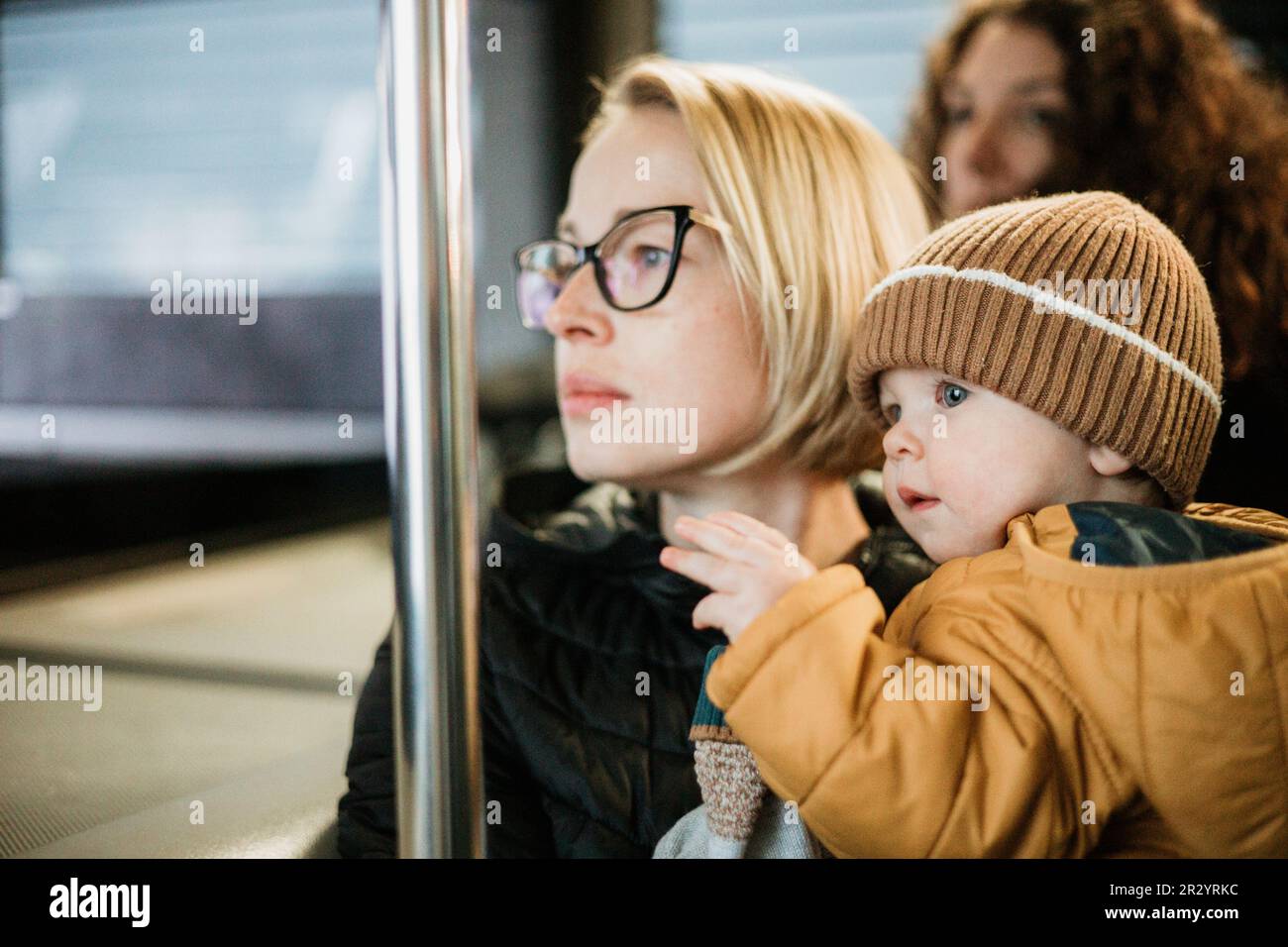 Mother carries her child while standing and holding on to the bus. Mom ...