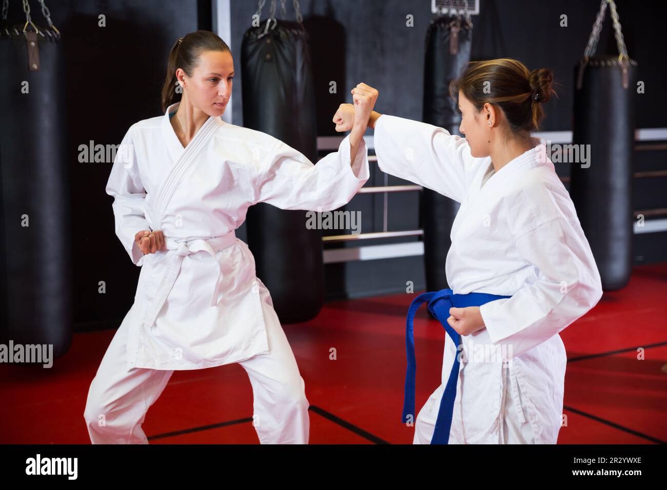 Portrait of woman wearing white kimono sparring with female opponent during martial arts ...