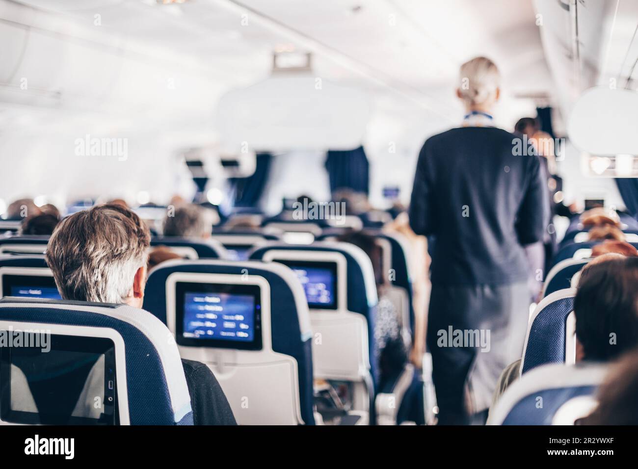 Interior of airplane with passengers on seats and stewardess in uniform ...