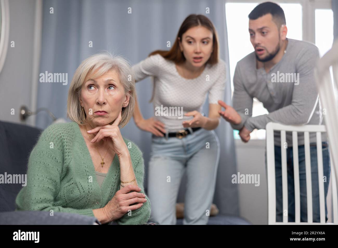 Senior woman ignoring adult couple scolding her Stock Photo - Alamy