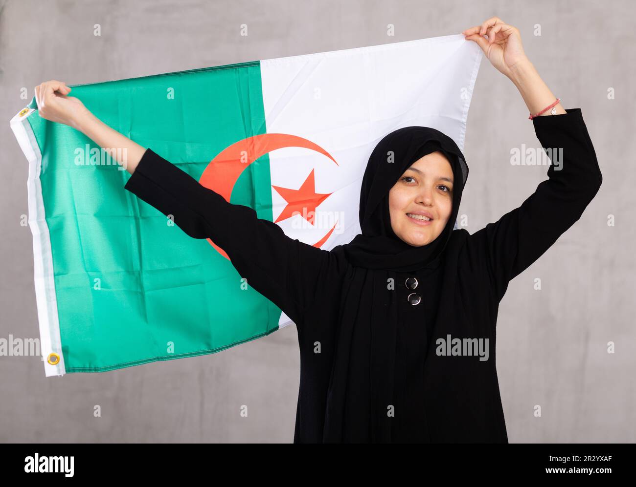 Young Muslim woman in black hijab holds unfurled flag of Algeria Stock ...