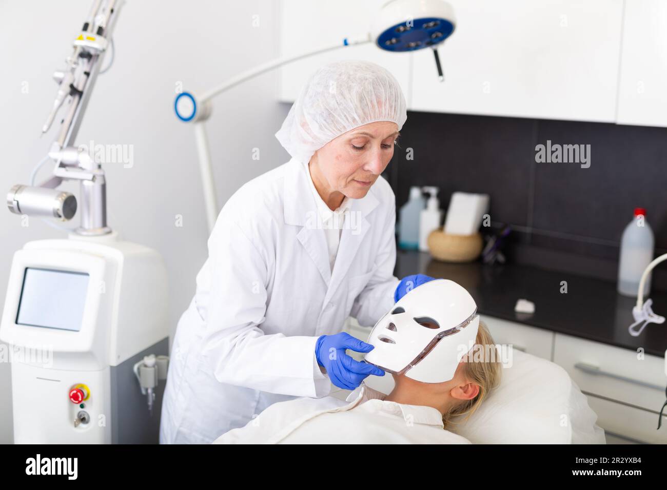 Cosmetologist using spectrum mask on young woman Stock Photo - Alamy