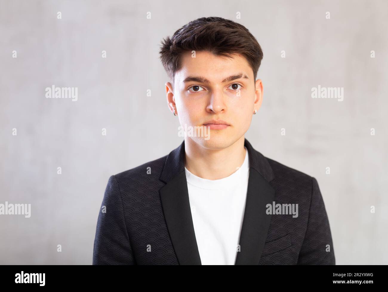 Positive male student in black jacket poses with folded arms on chest ...