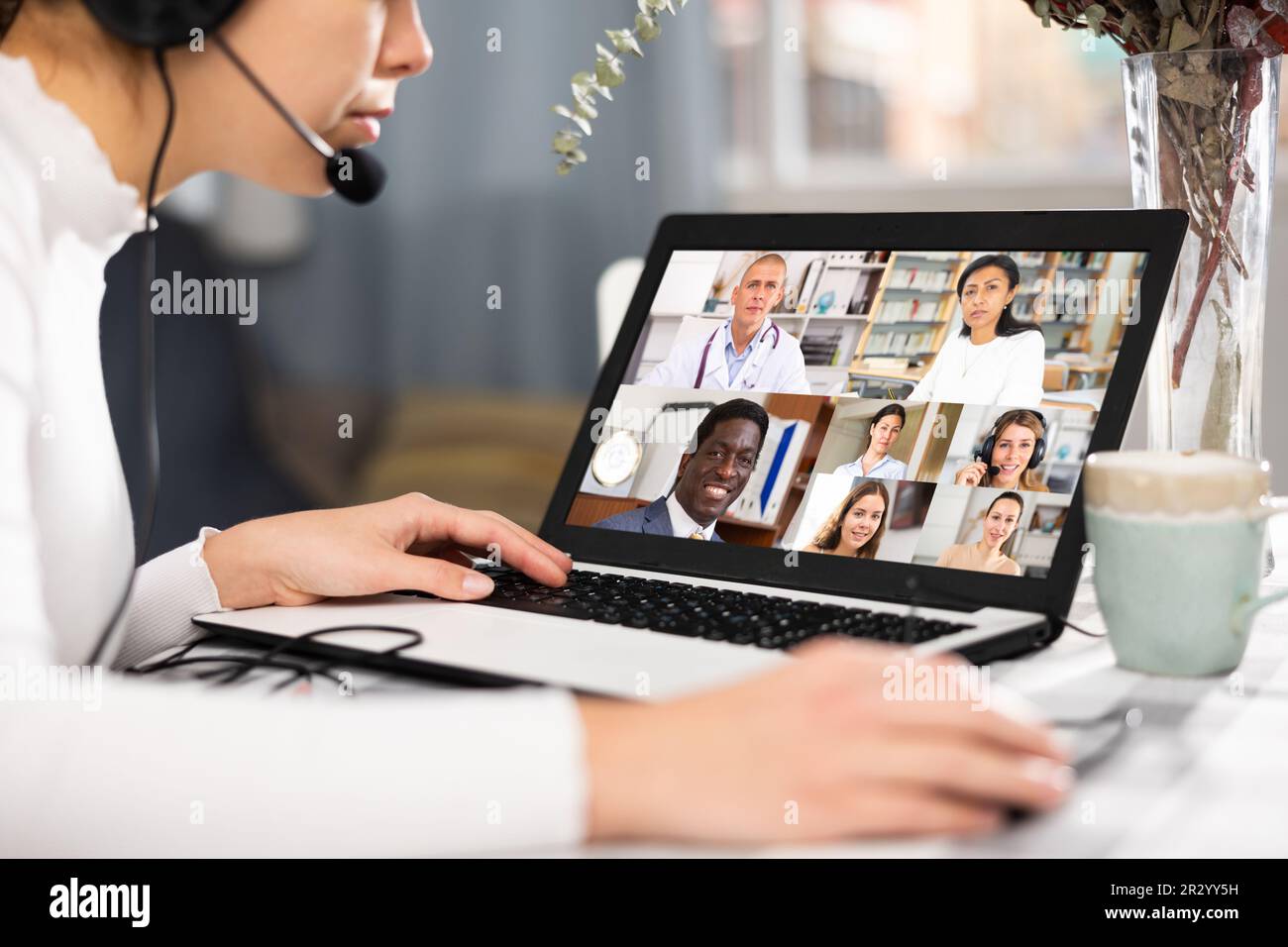 Young woman having video call conversation with co-workers at home ...