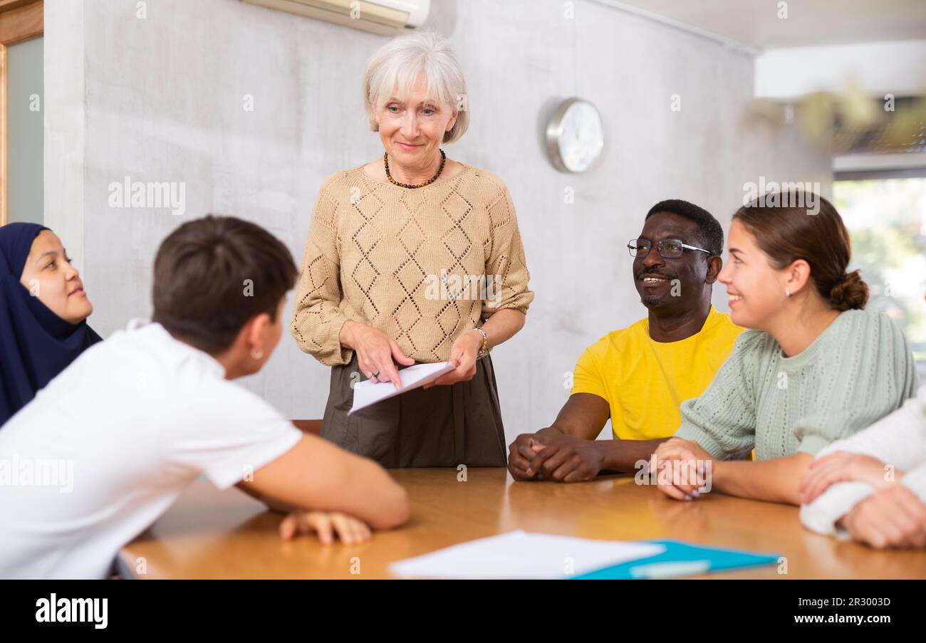 Elderly manager holds round table meetings for employees of different ...