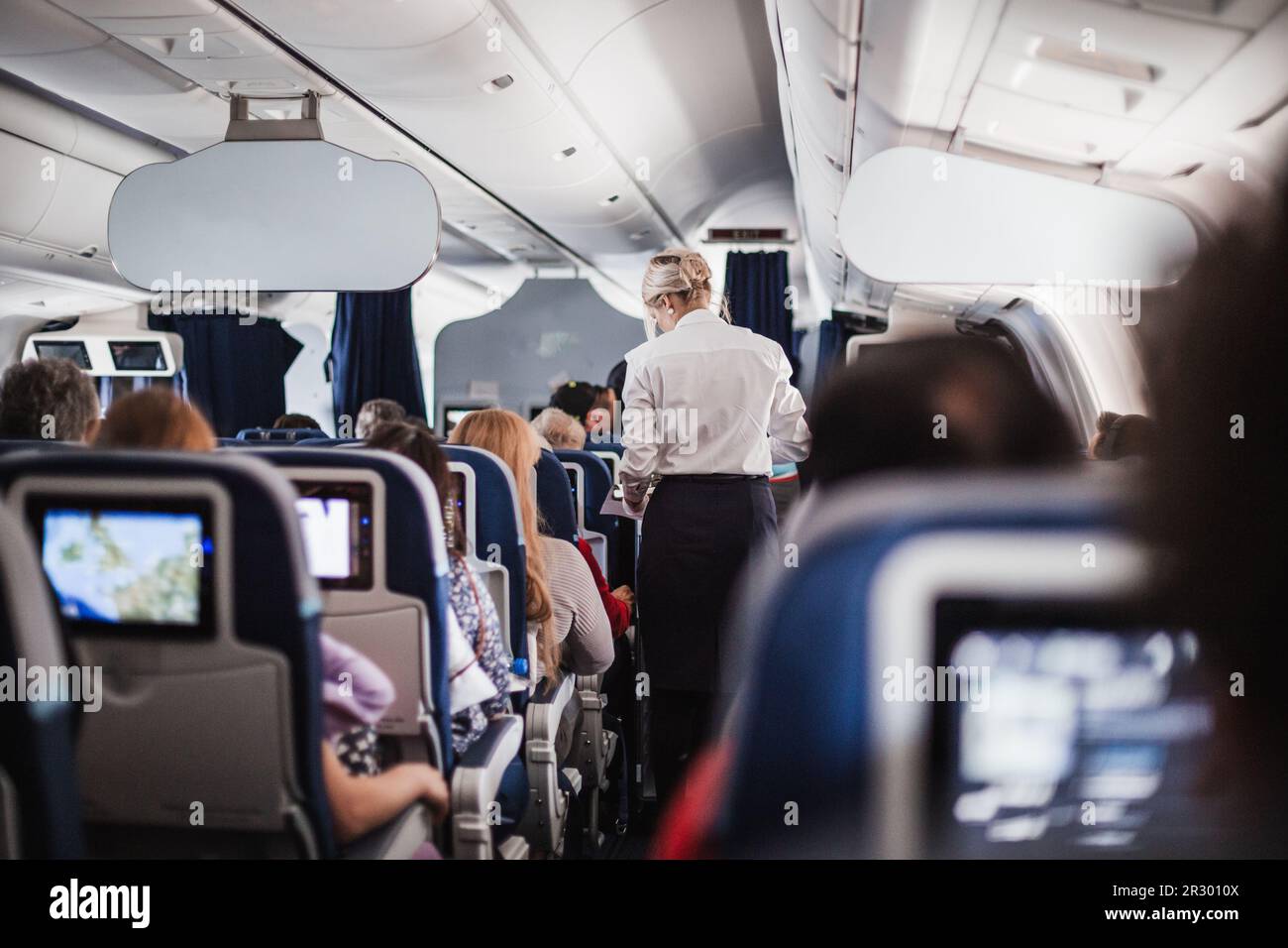 Interior of airplane with passengers on seats and stewardess in uniform ...
