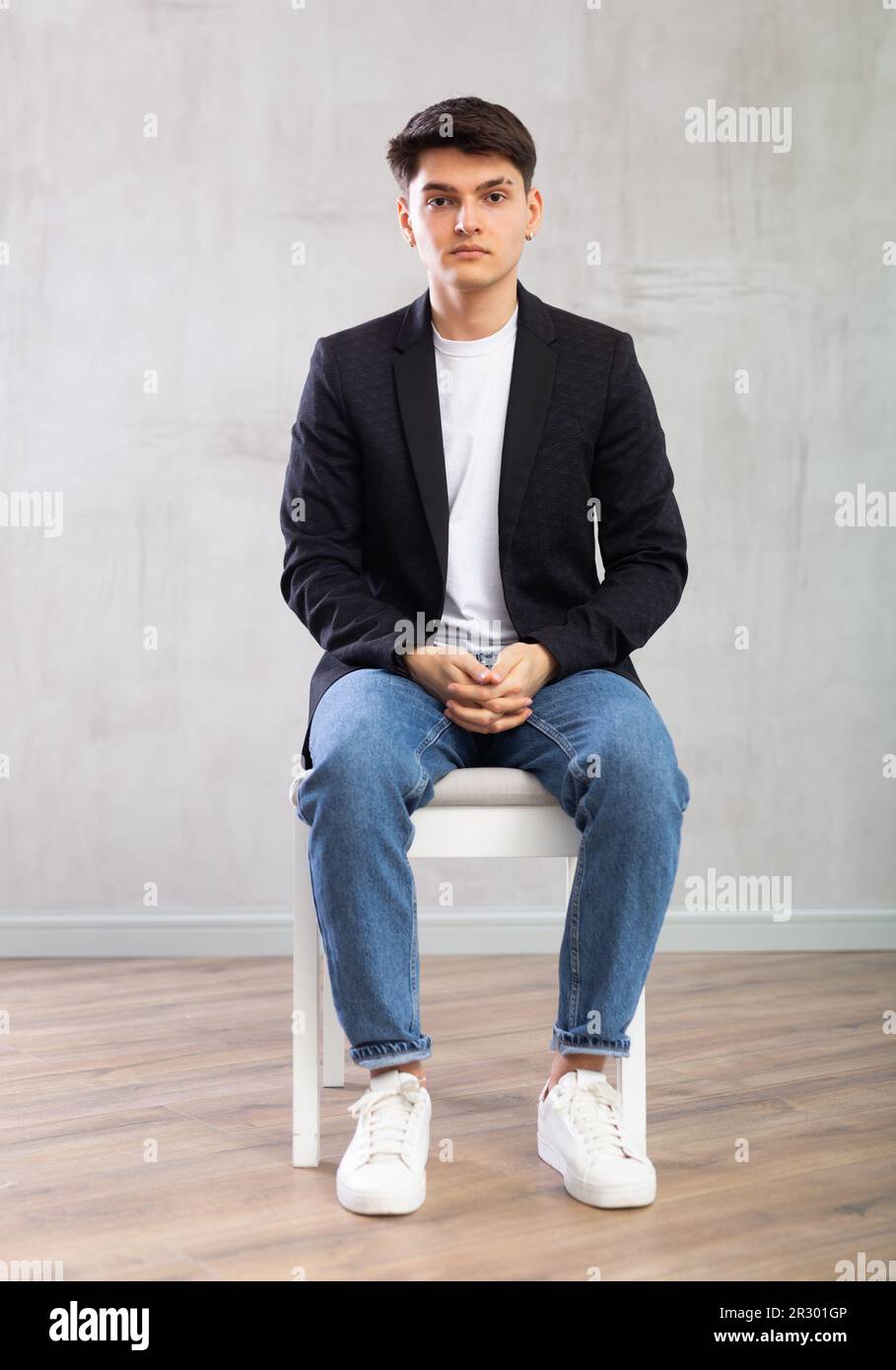 Charismatic young man sitting on chair in the middle of the room Stock ...