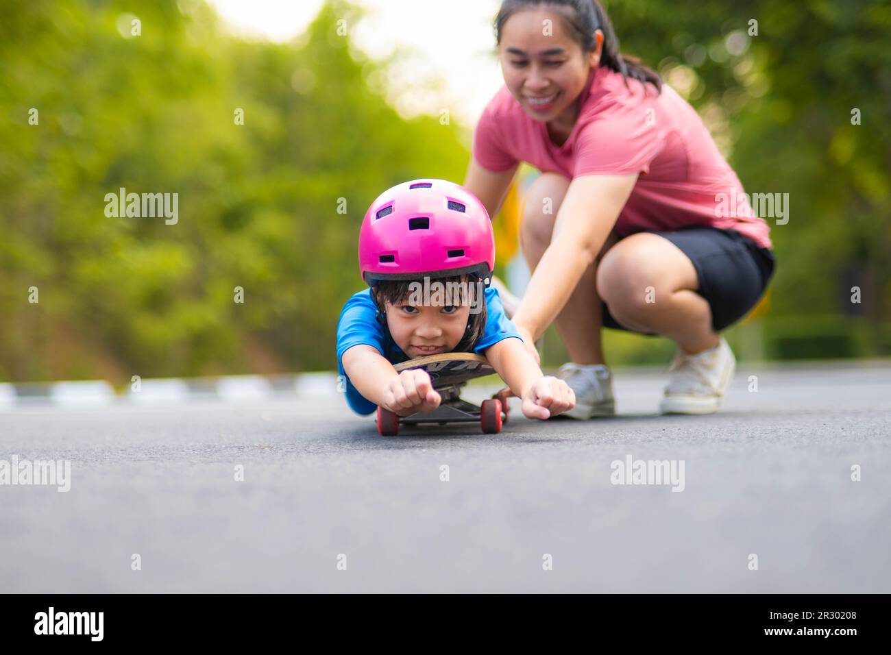 Active little girl and mom enjoy skateboarding. Cute little girl ...