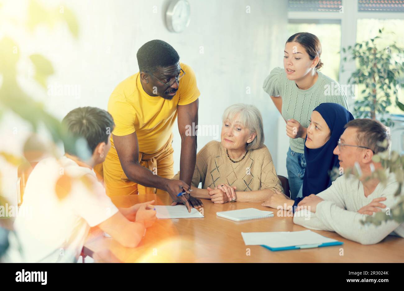 African American tutor conducting lesson for group of adult people ...