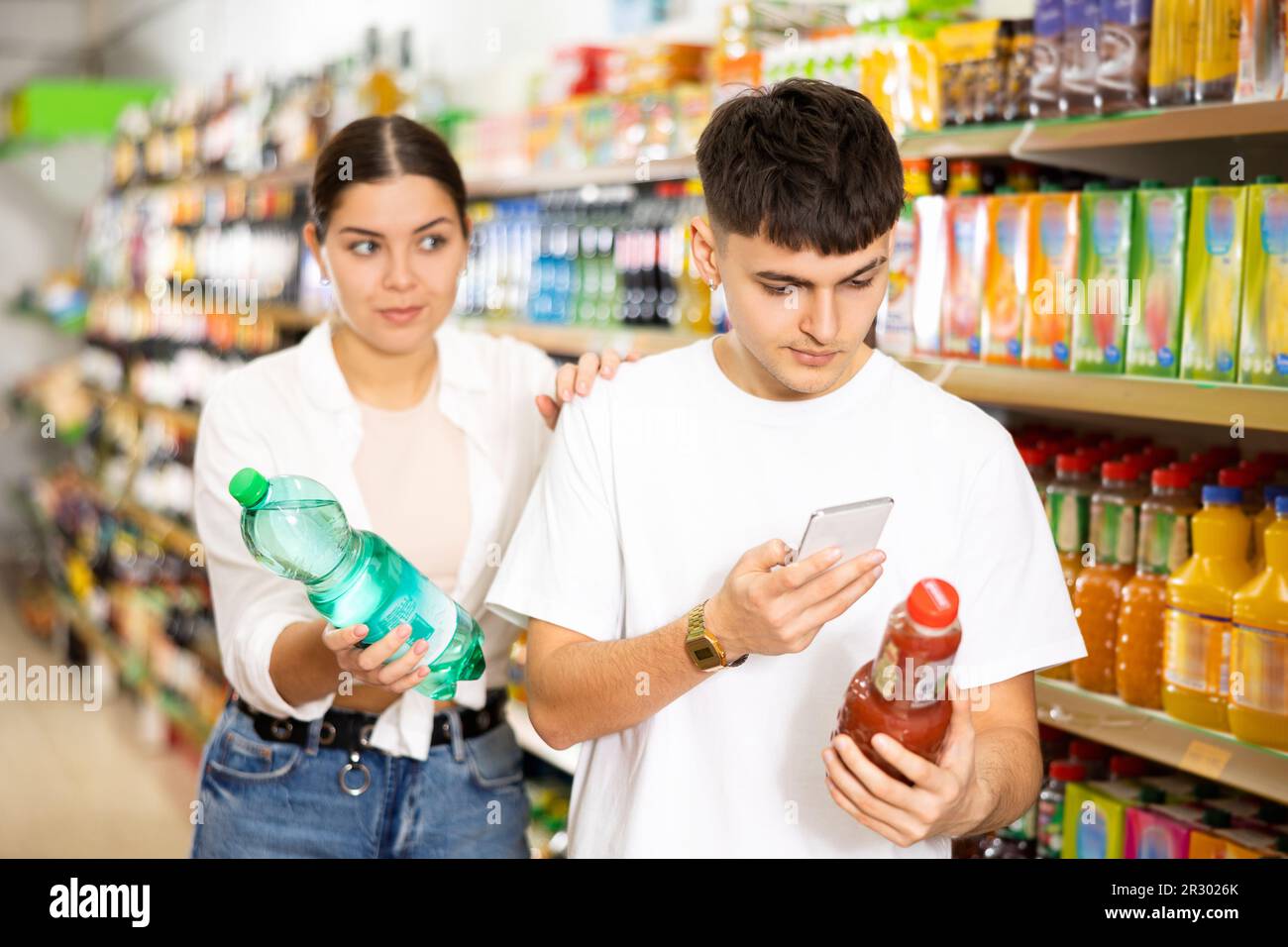 in shop, man and woman chooses drink. Guy scans QR code from label on ...