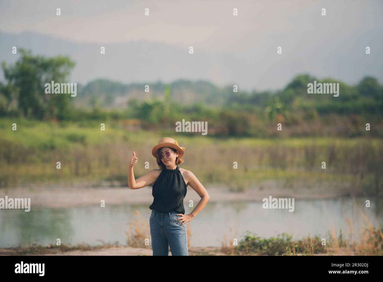 beautiful asian woman standing on open land scape and raising right ...