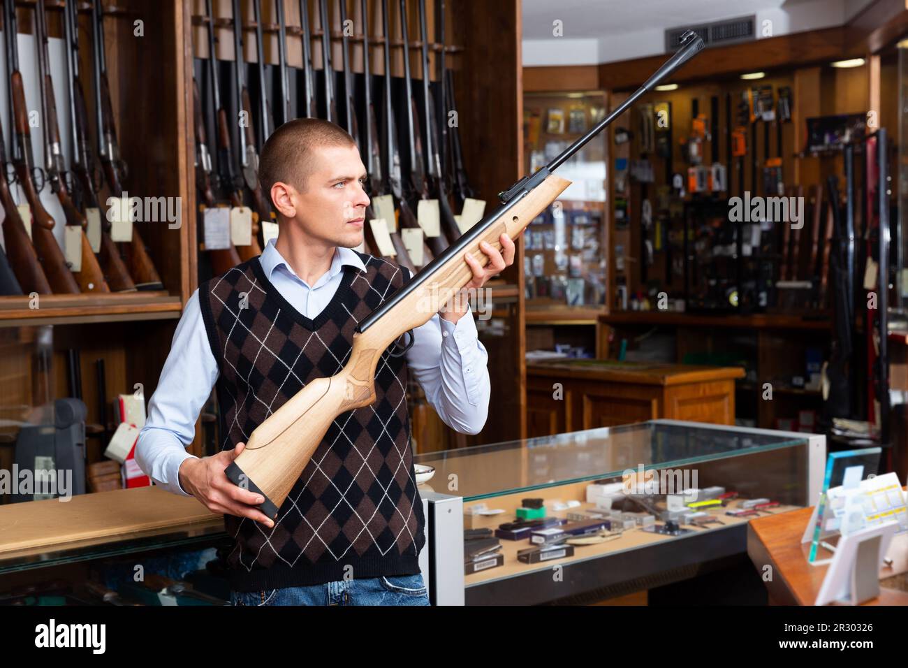 Man choosing hunting break barrel rifle in gun shop Stock Photo - Alamy