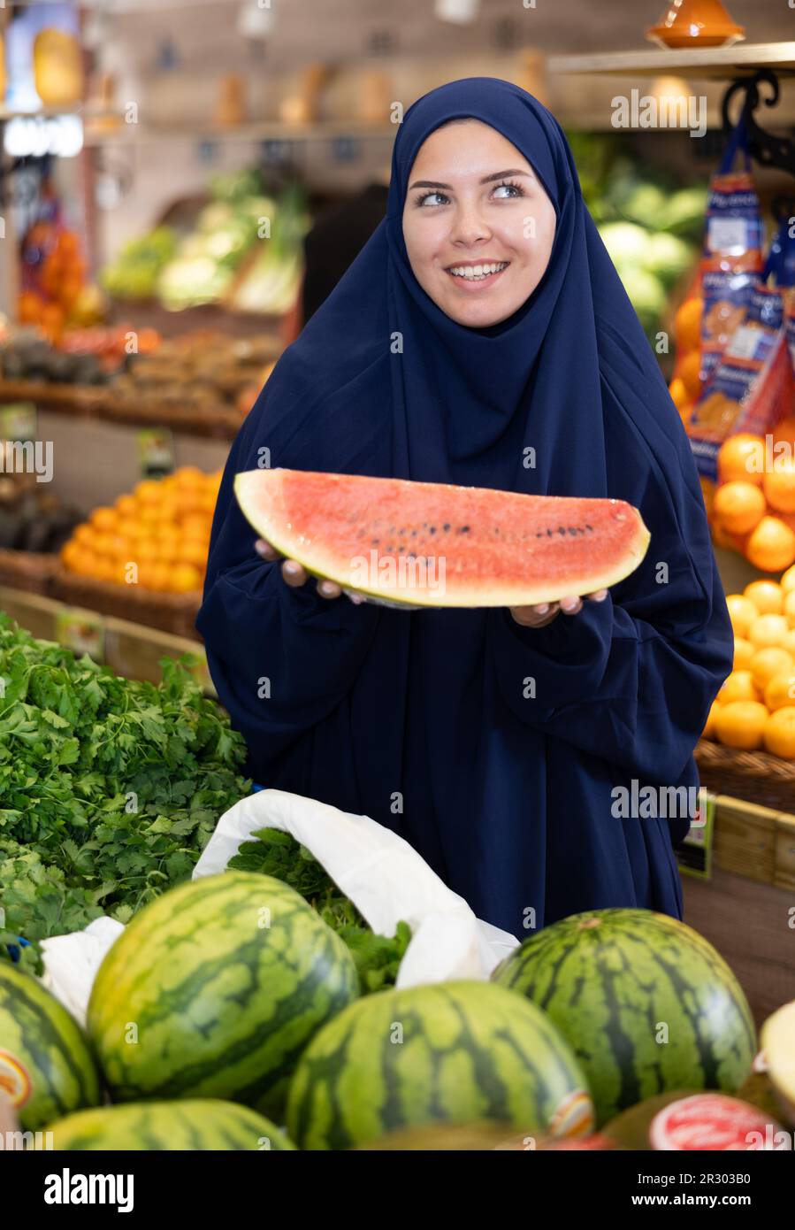 Girl in veil carefully chooses fresh watermelon in supermarket Stock ...