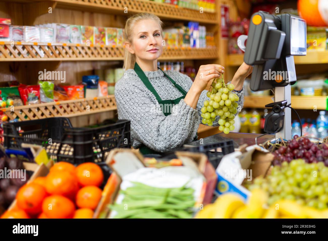 Focused saleswoman weighing grape on scale in grocery store Stock Photo ...