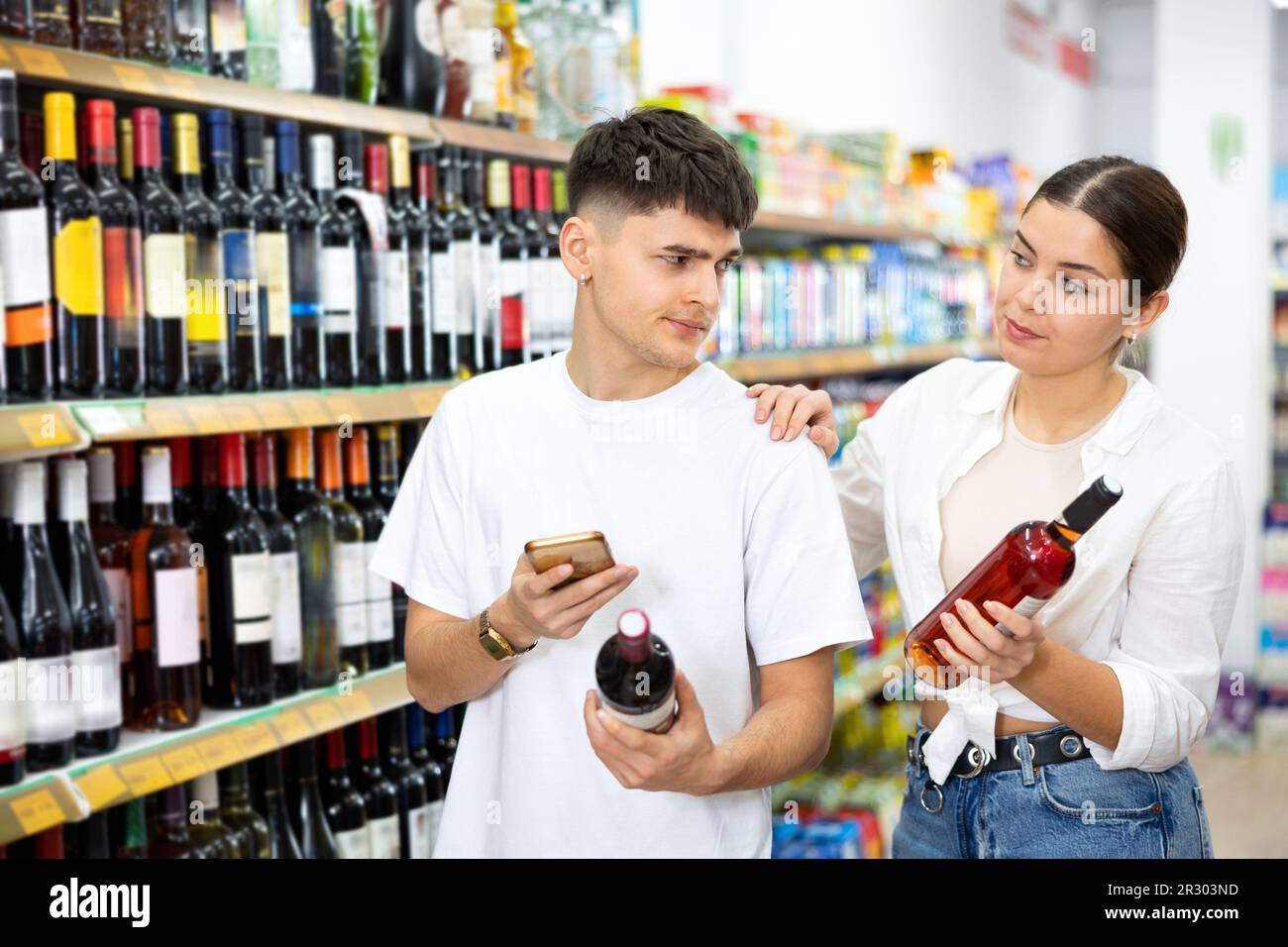 Young couple scanning barcodes on bottles of alcoholic beverages with ...