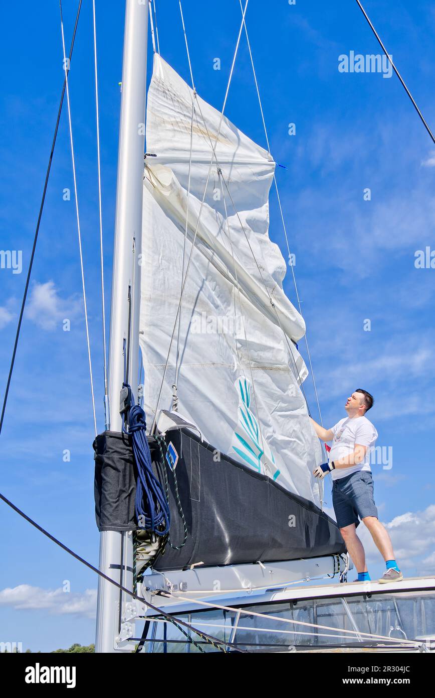 Raising the sail on a yacht. Young man captan lifting the sail of ...