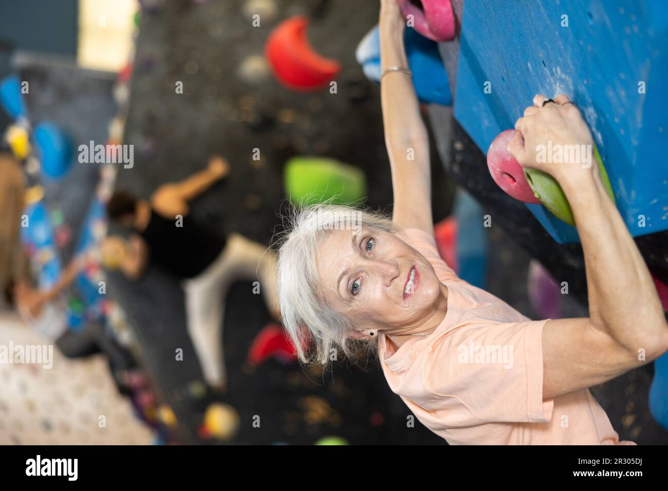 Determined old lady doing difficult wall climb in climbing gym Stock ...
