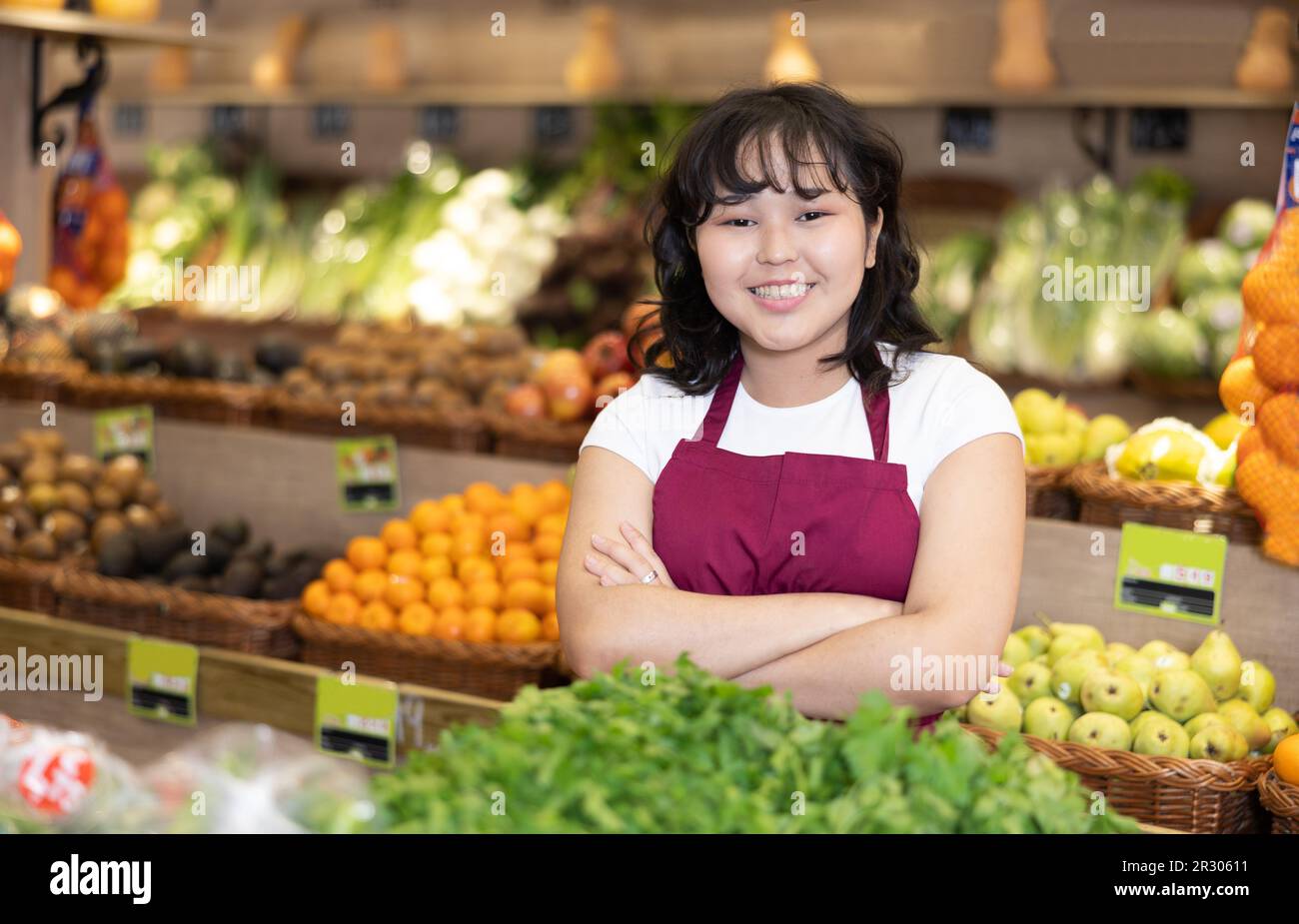 Young saleswoman standing in front of counter in grocery store Stock ...