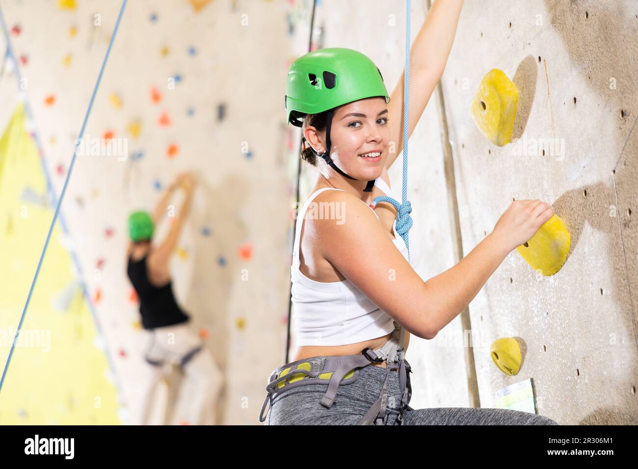 Positive extreme young woman with rope training on concrete climbing ...