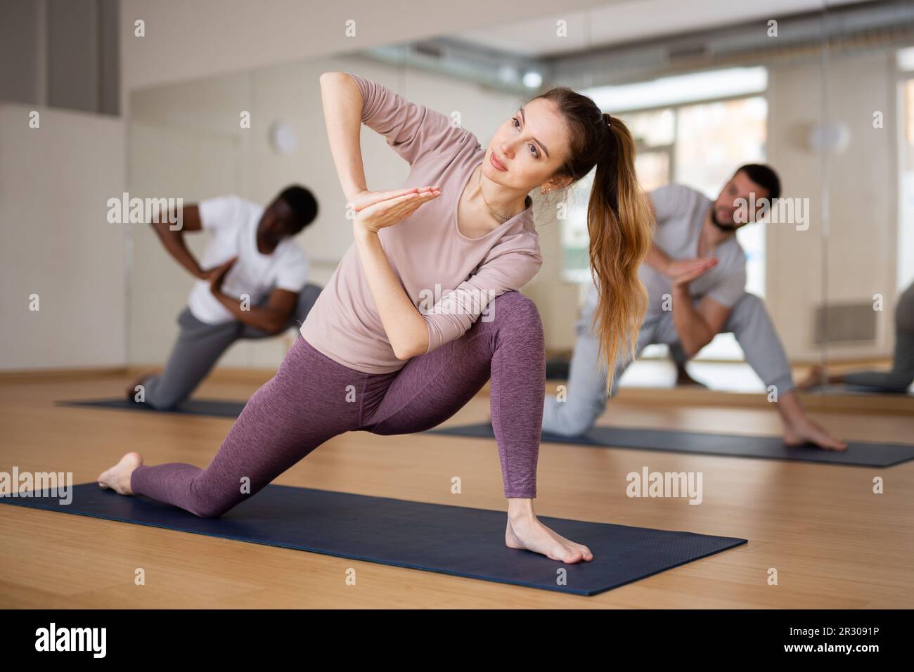 Woman doing yoga postures on group training Stock Photo - Alamy