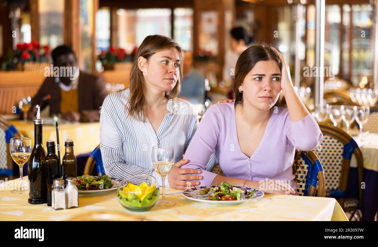 Woman calming upset female friend in restaurant during dinner Stock ...