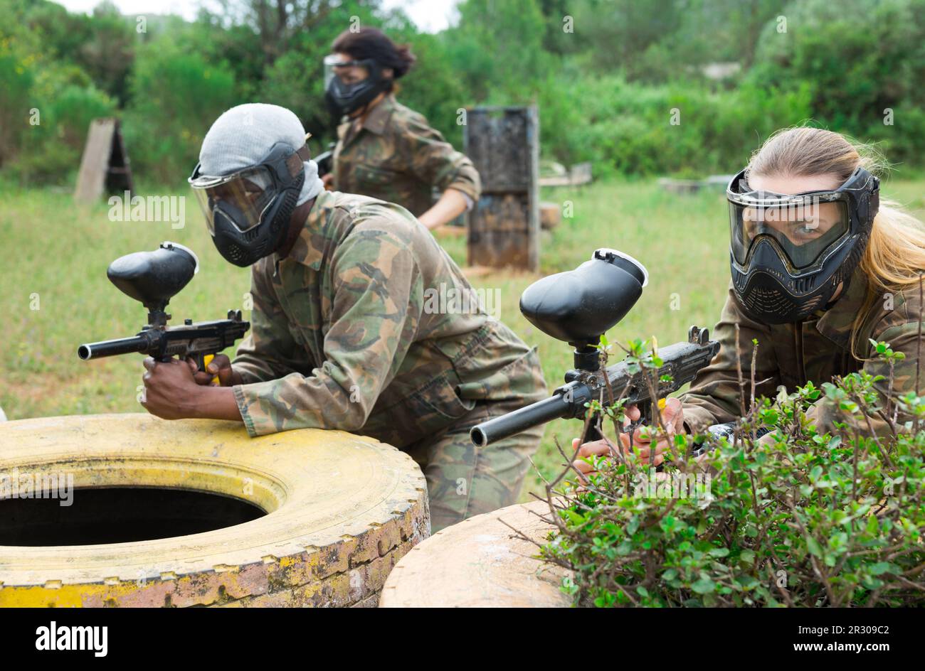 Group of people in full gear playing paintball on shooting range ...