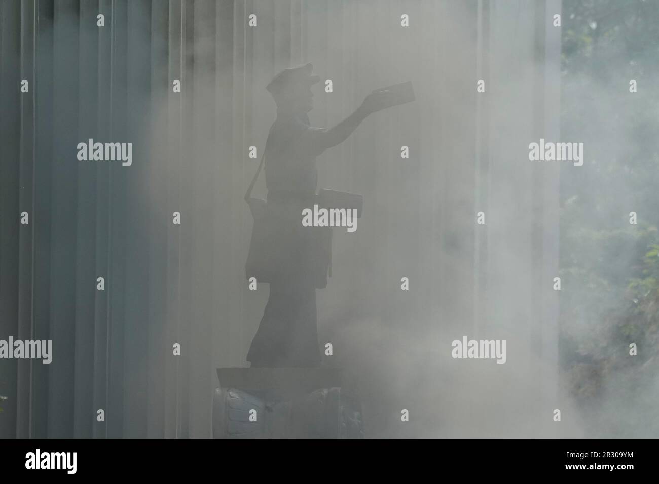 A statue of a postman is enveloped in smoke in front of the Manila ...