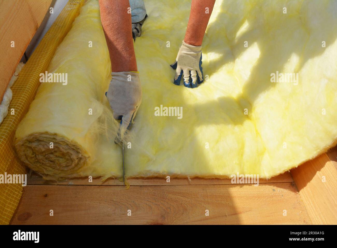 Roofer contractor insulating house roof and cutting mineral wool with a ...